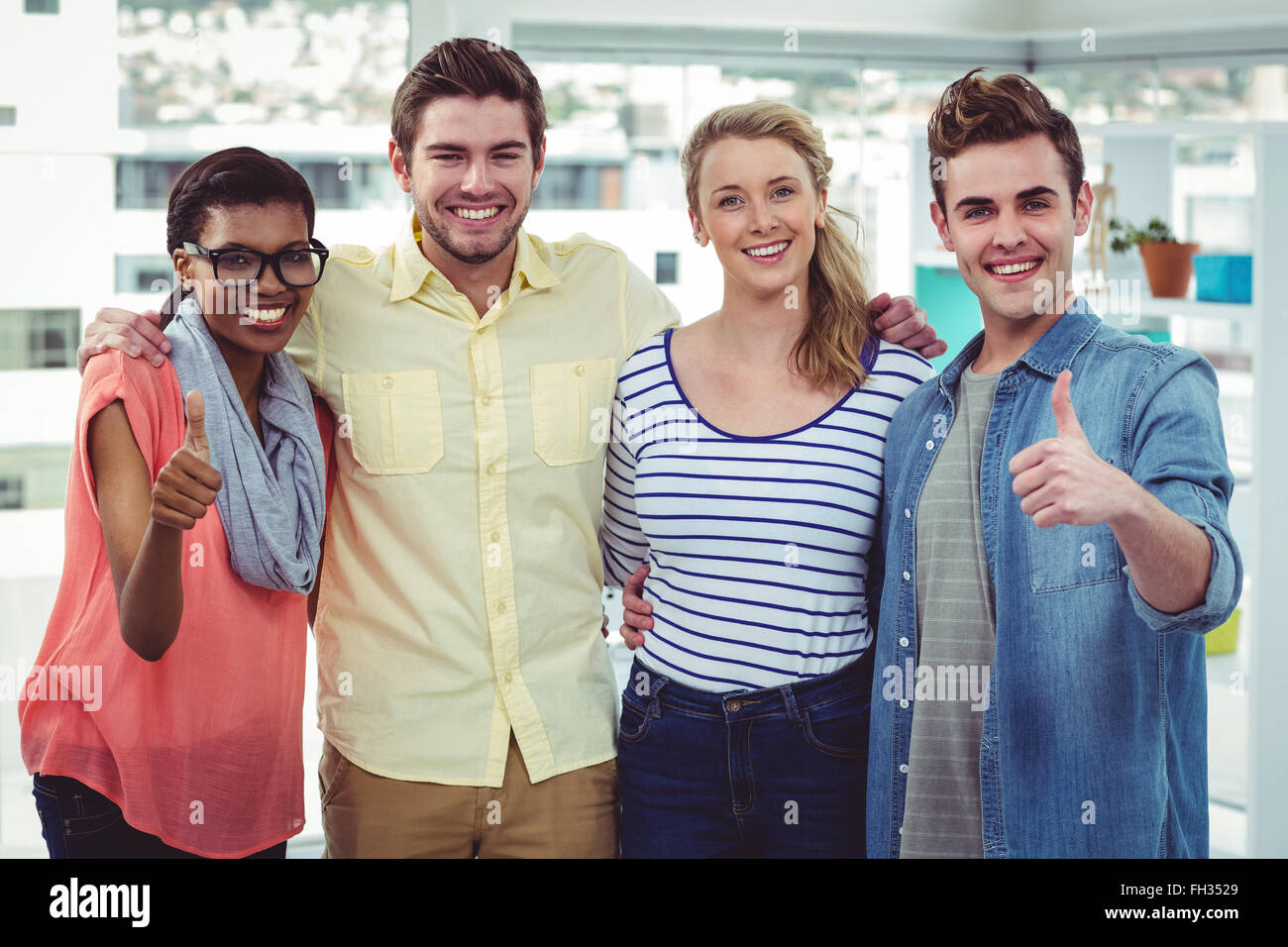 Happy creative team giving the thumbs up Stock Photo - Alamy