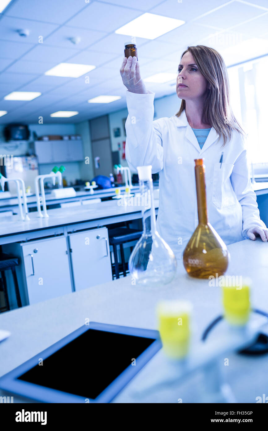 Scientist looking at beaker of chemical Stock Photo - Alamy