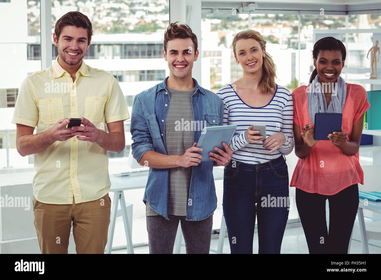 Smiling creative team standing in a line using technology Stock Photo ...