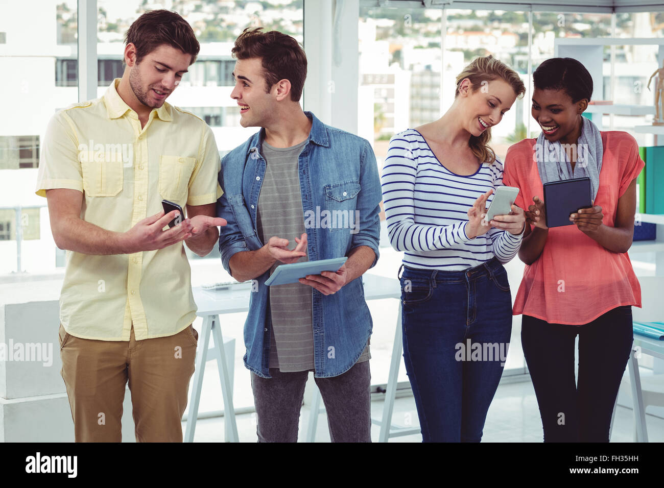 Smiling creative team standing in a line using technology Stock Photo ...