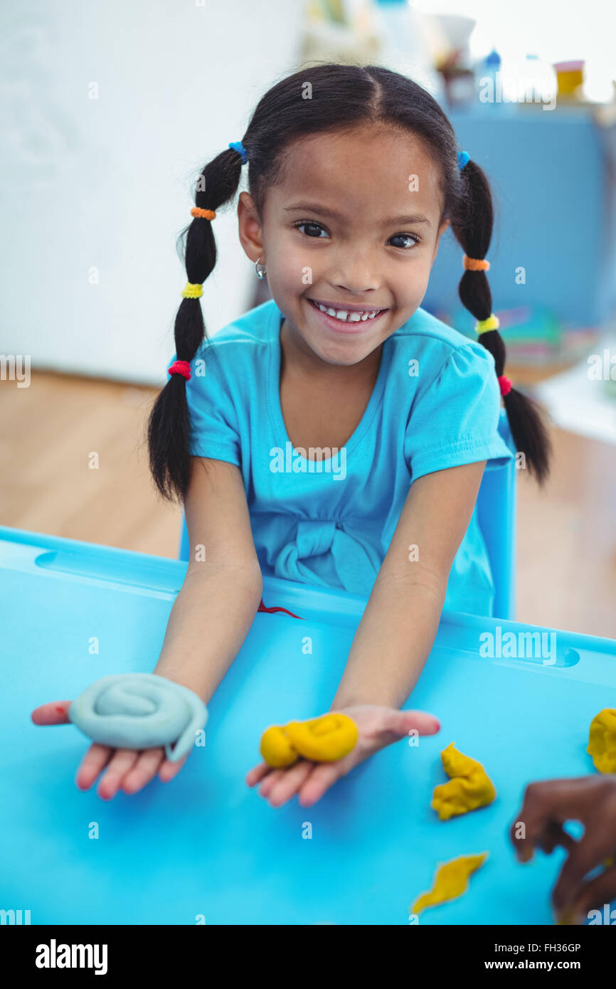 Smiling girl using modelling clay Stock Photo - Alamy