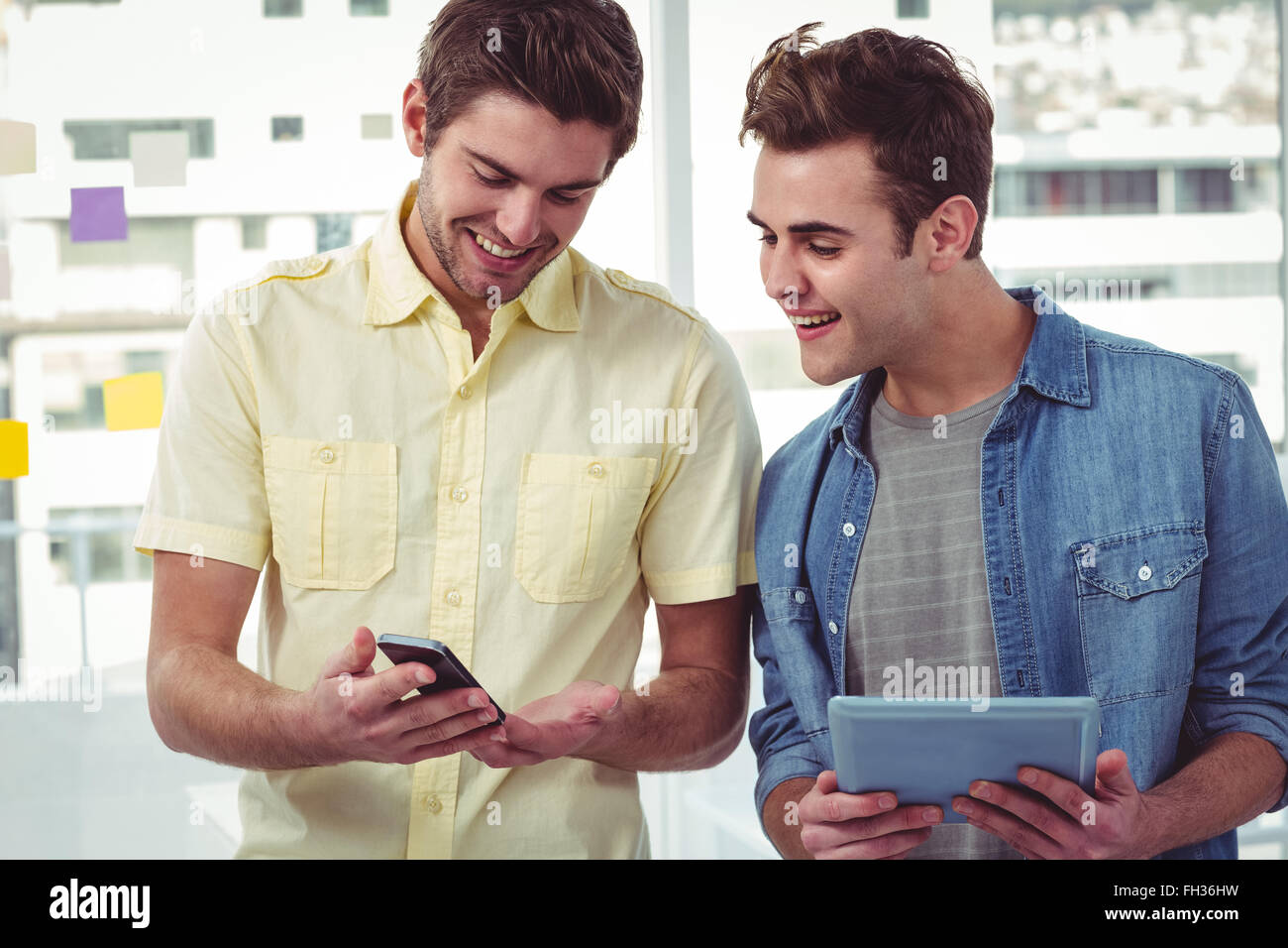 Smiling creative team standing in a line using technology Stock Photo ...