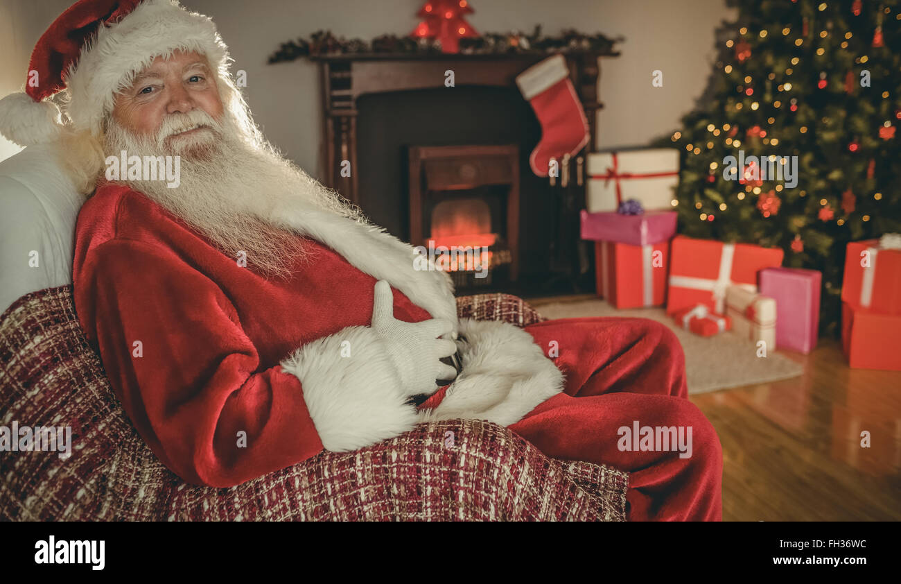 Smiling santa sitting and holding his belly Stock Photo - Alamy