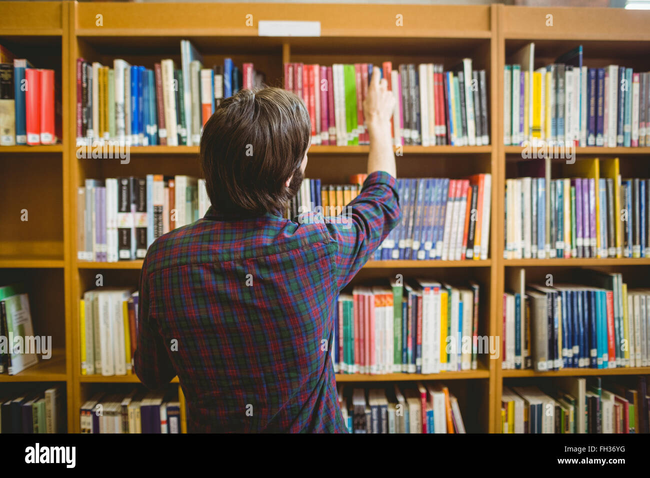 Student picking a book from shelf in library Stock Photo - Alamy