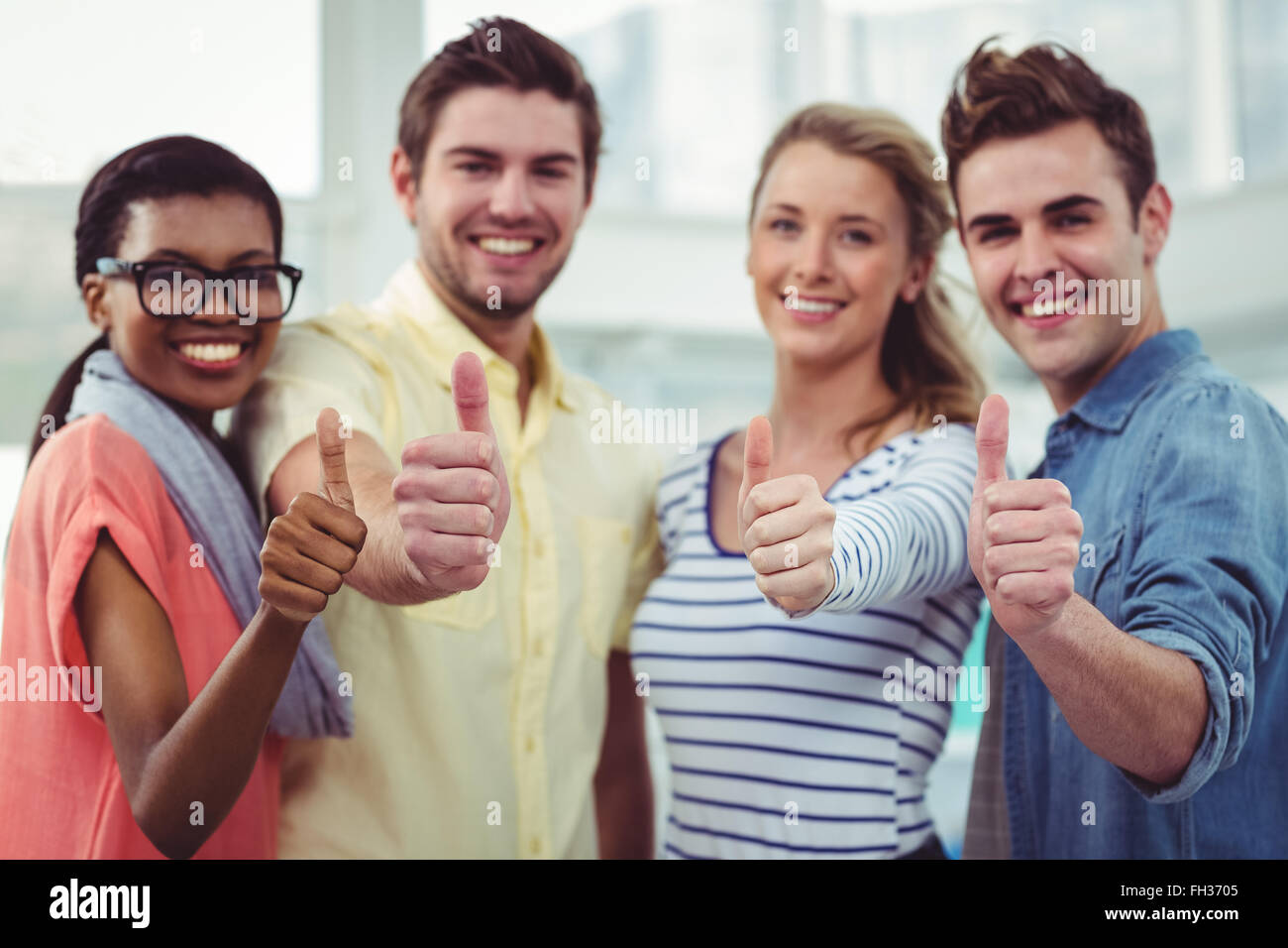 Happy creative team giving the thumbs up Stock Photo - Alamy