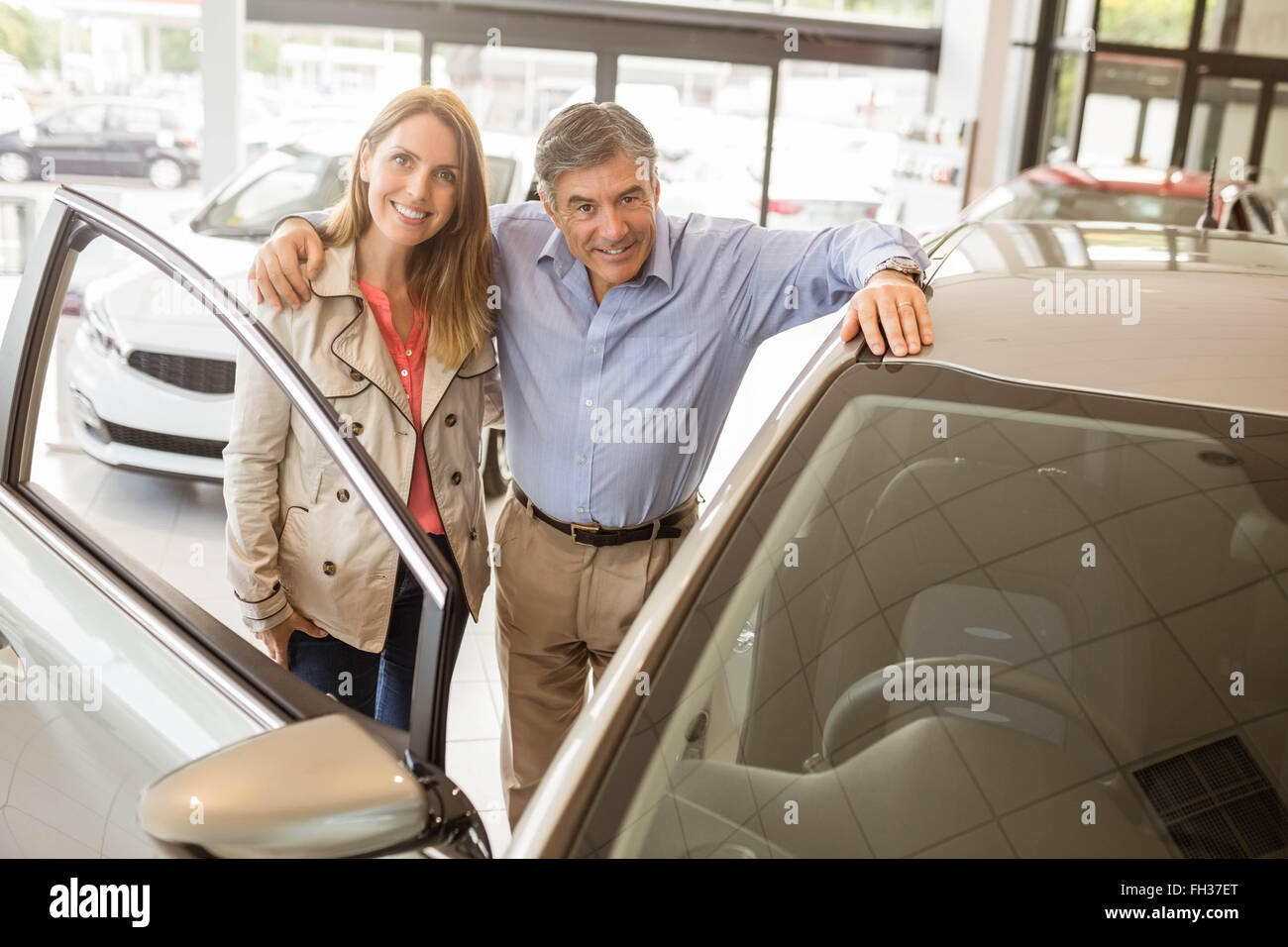 Smiling couple leaning on car Stock Photo - Alamy