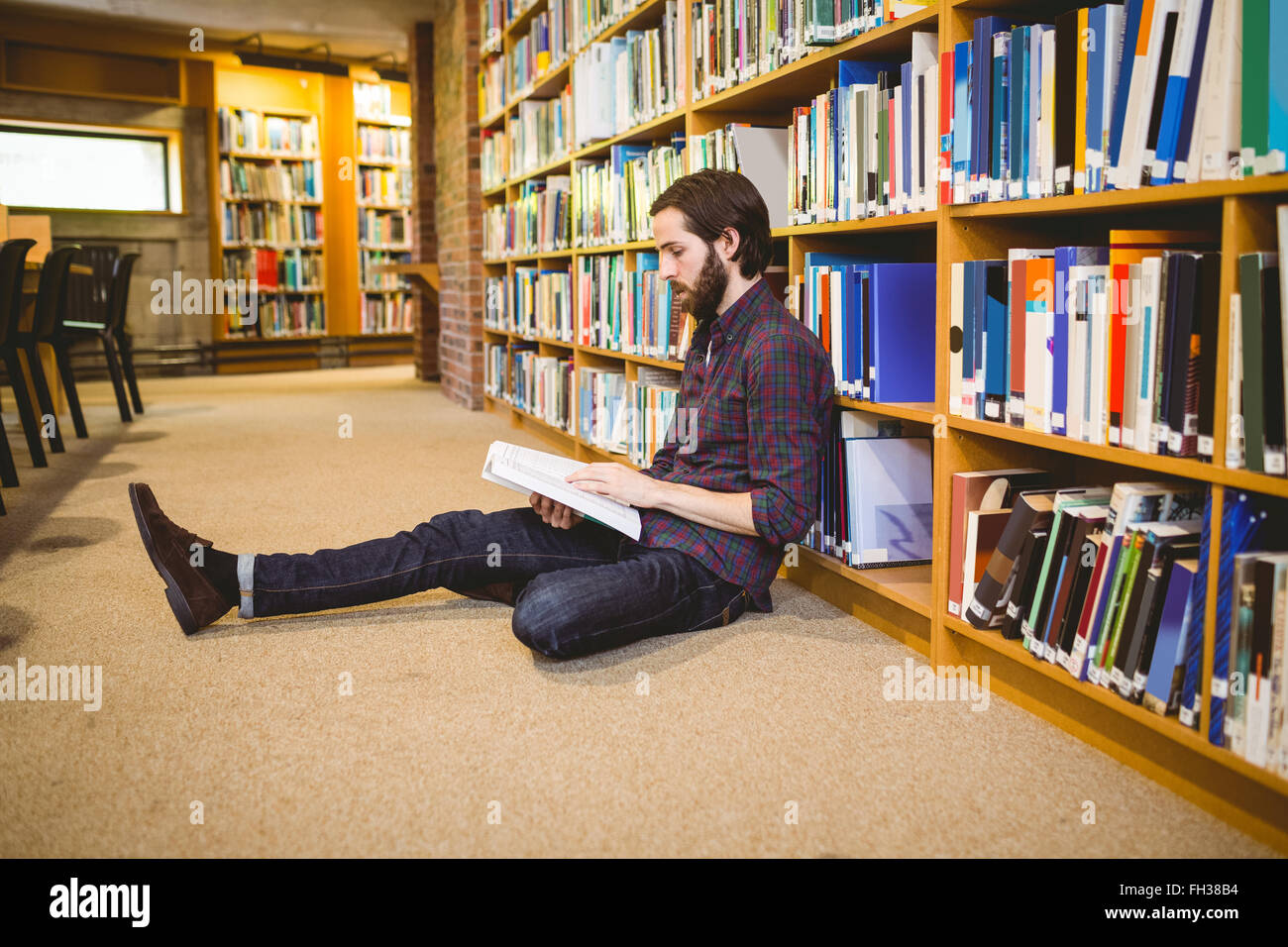 Student reading book in library on floor Stock Photo - Alamy