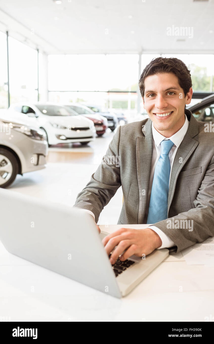 Smiling salesman writing on his laptop Stock Photo - Alamy
