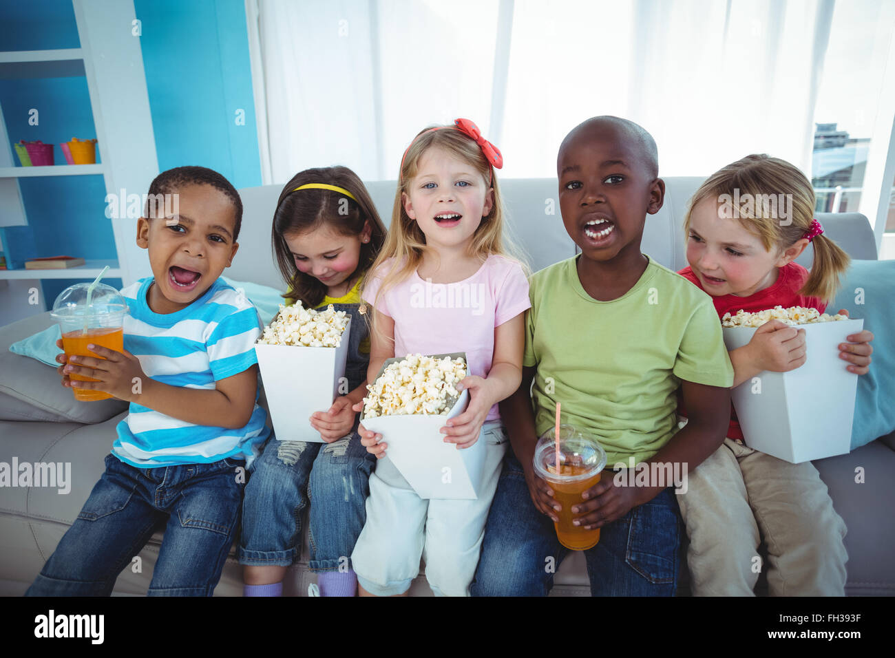 Happy kids enjoying popcorn and drinks while sitting Stock Photo - Alamy