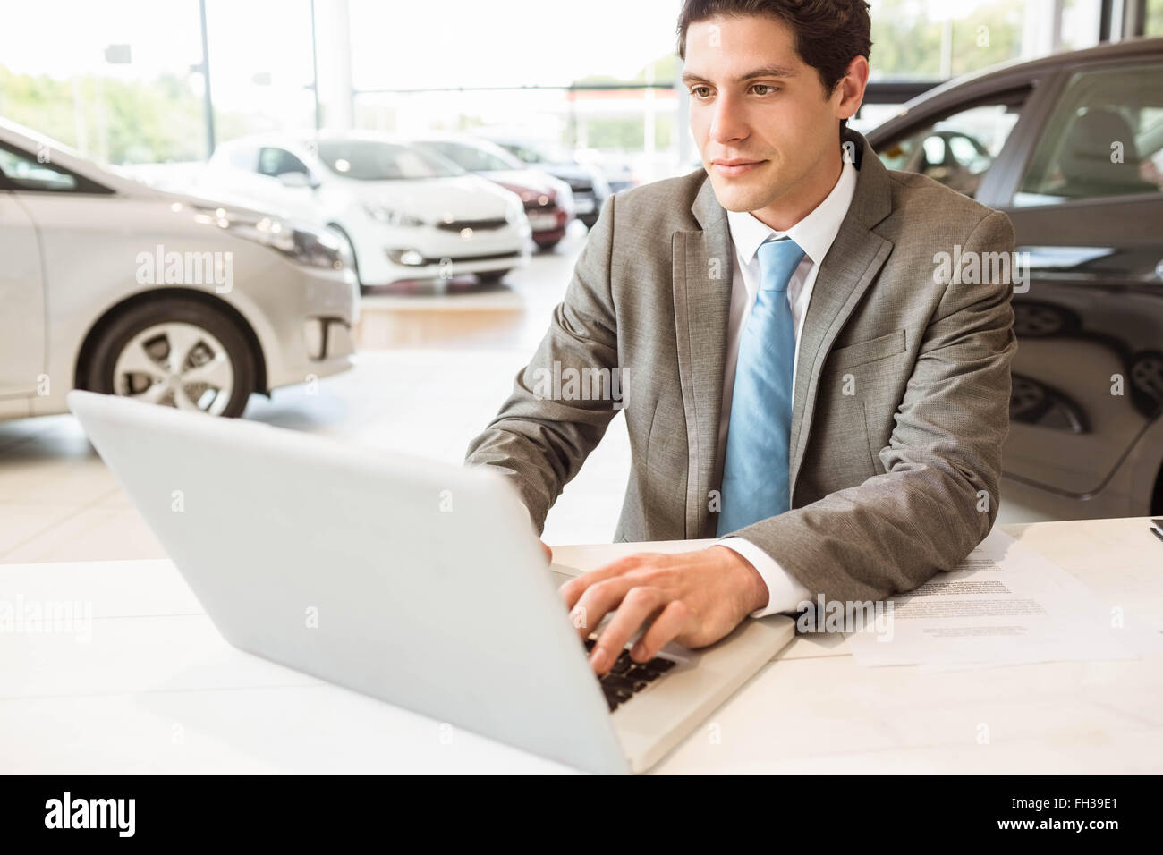 Smiling salesman writing on his laptop Stock Photo - Alamy