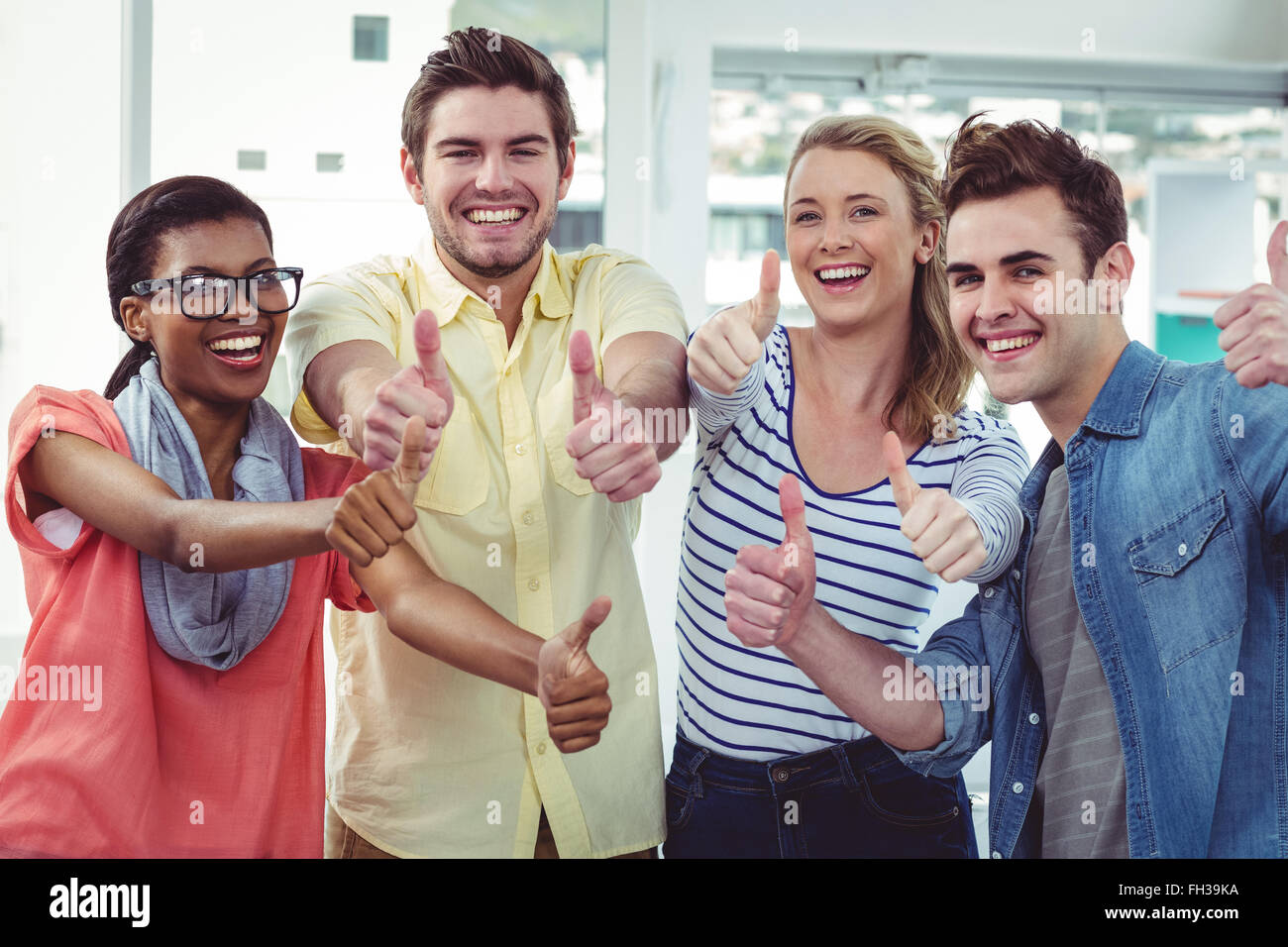 Happy creative team giving the thumbs up Stock Photo - Alamy