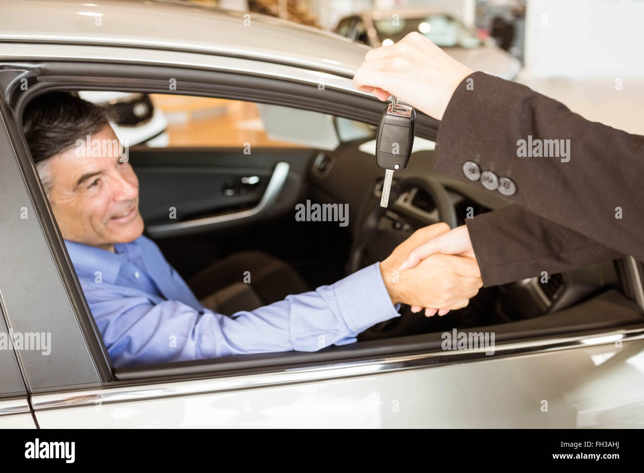 Customer receiving car keys while shaking hand Stock Photo - Alamy