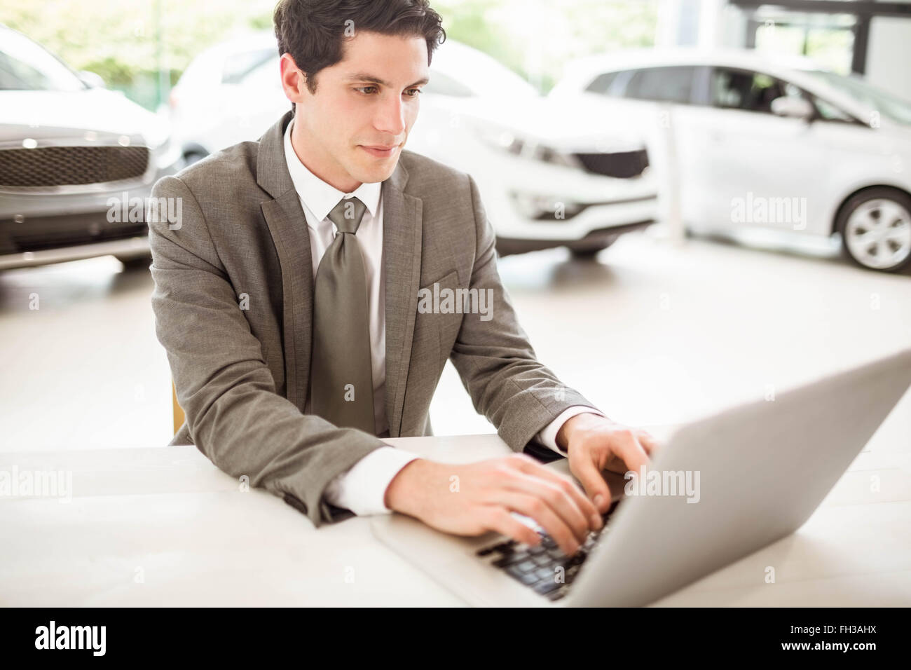 Smiling salesman typing on his laptop Stock Photo - Alamy