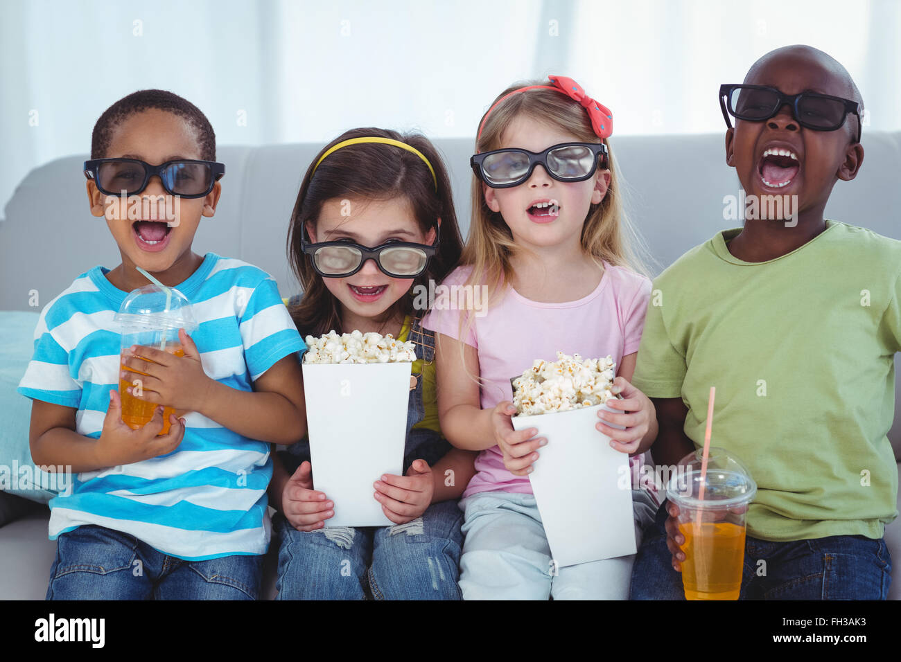 Happy kids enjoying popcorn and drinks while sitting Stock Photo - Alamy