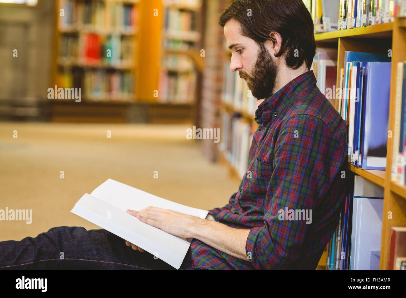 Student reading book in library on floor Stock Photo - Alamy