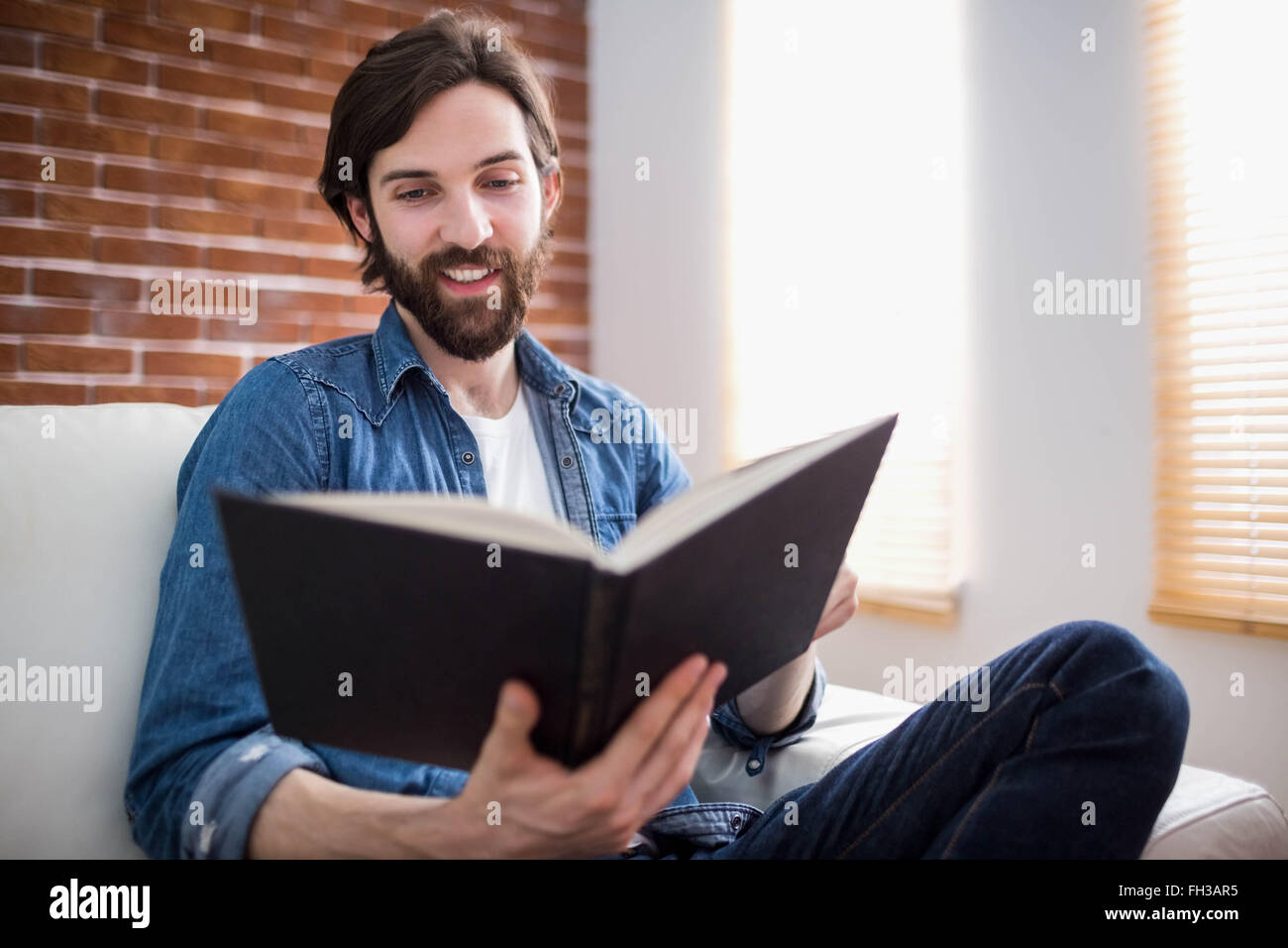 Casual man reading on his sofa Stock Photo - Alamy
