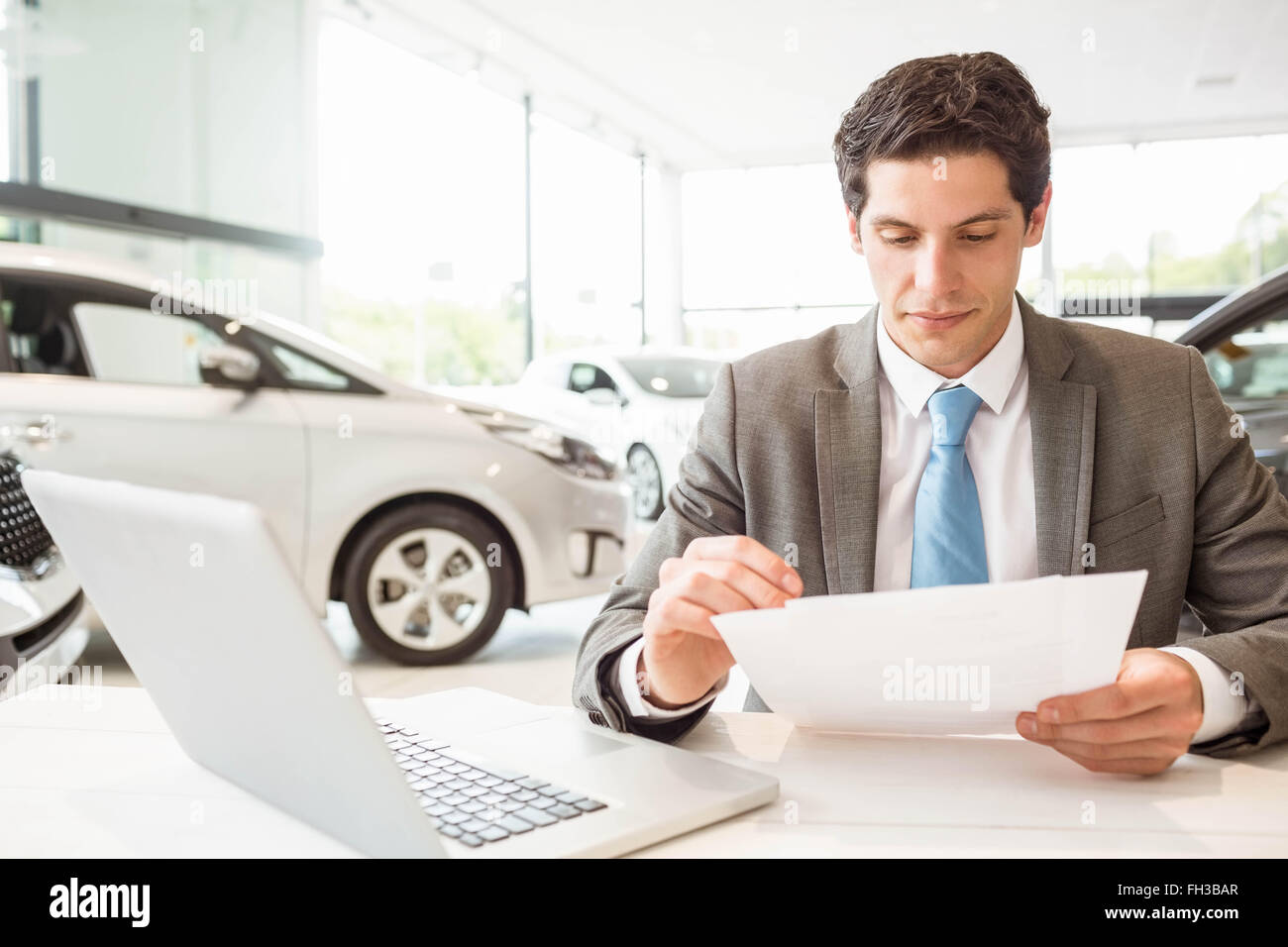 Smiling salesman reading a document Stock Photo - Alamy