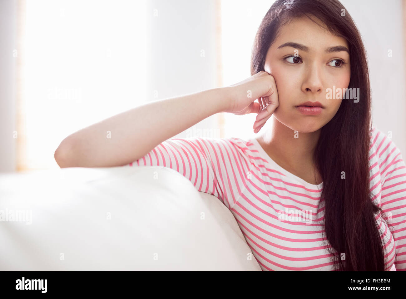 Upset asian woman on couch Stock Photo - Alamy