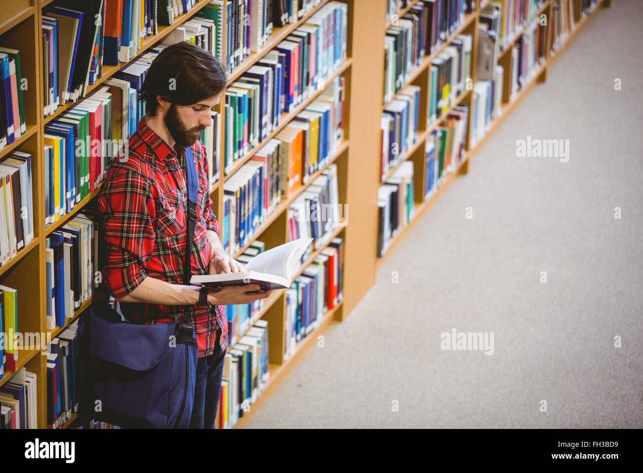Student reading a book from shelf in library Stock Photo - Alamy
