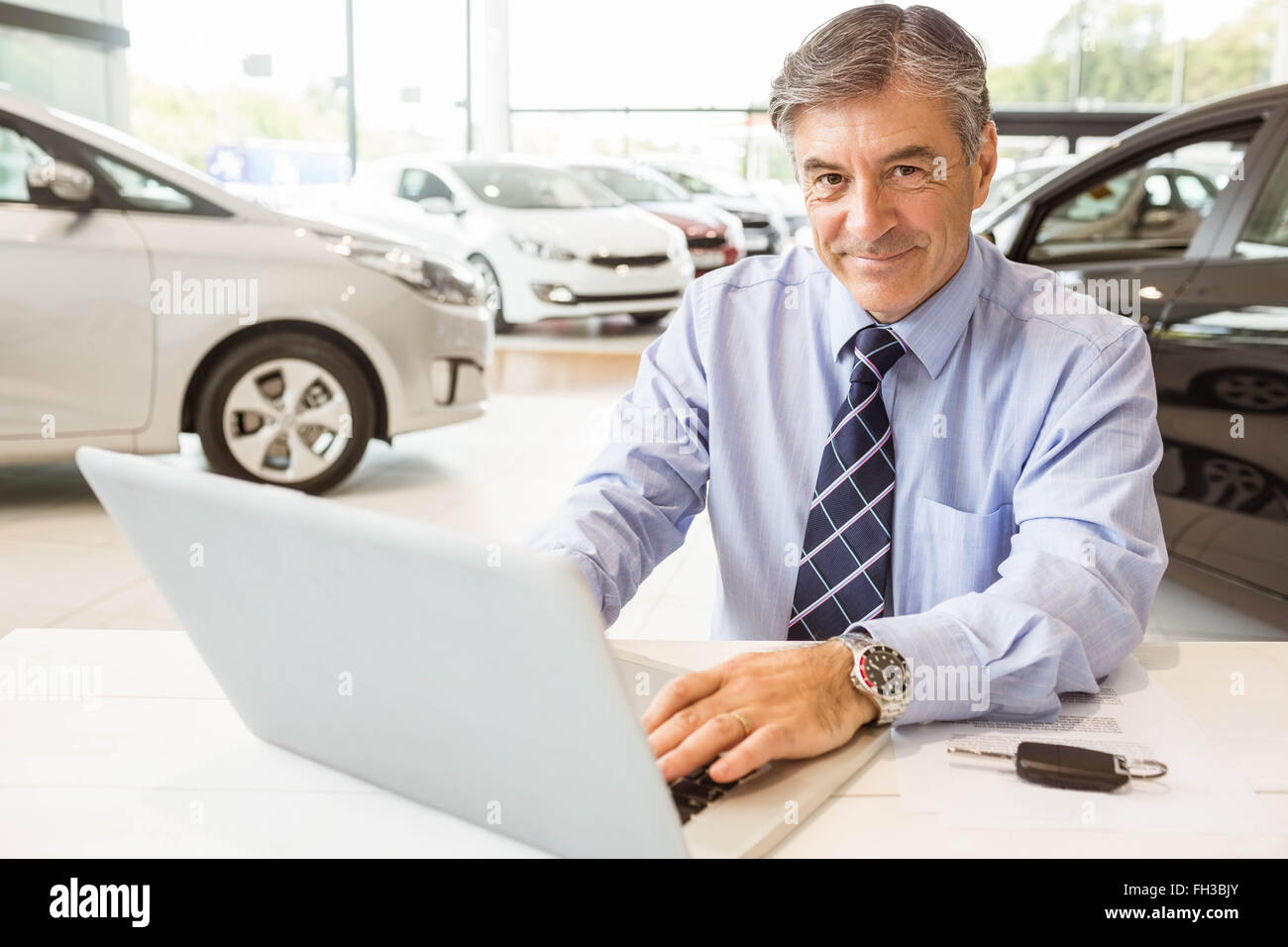 Smiling salesman behind his desk Stock Photo - Alamy