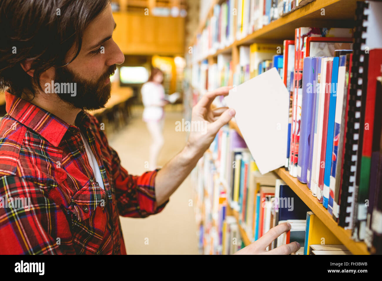 Hipster student picking a book in library Stock Photo - Alamy