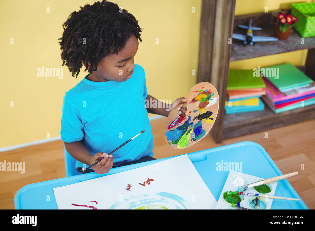 Child using paints to make a picture Stock Photo - Alamy
