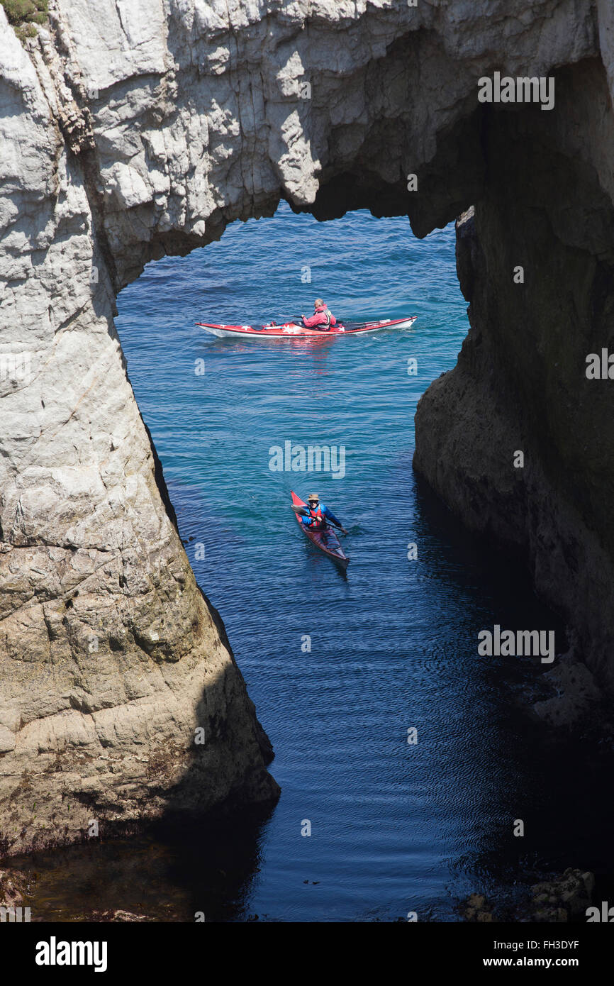 Two kayakers explore the sea under an arch on the north wales ...