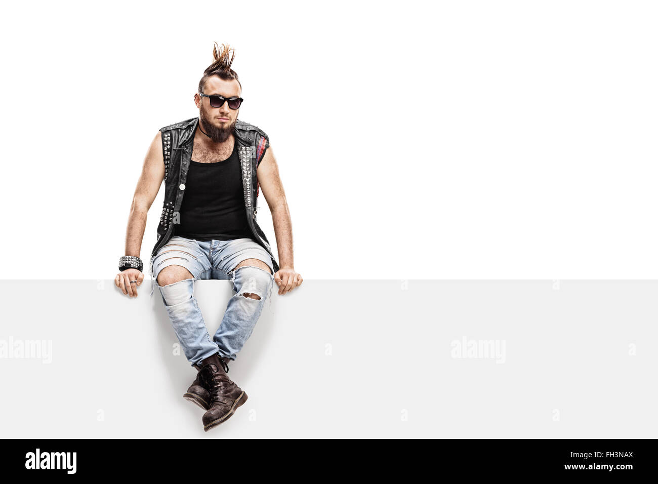 Young punk rocker with a Mohawk hairstyle and a leather vest sitting on ...