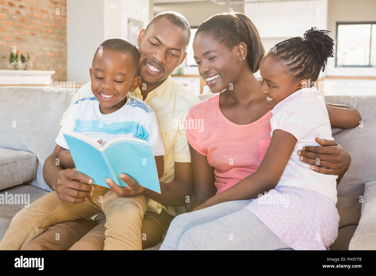 Happy family reading a book together Stock Photo - Alamy