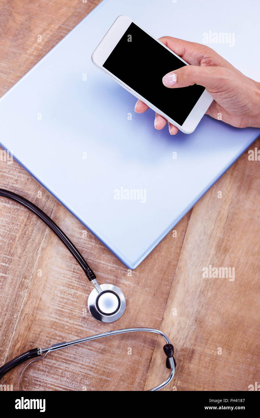 Doctor using smartphone on wooden desk Stock Photo - Alamy