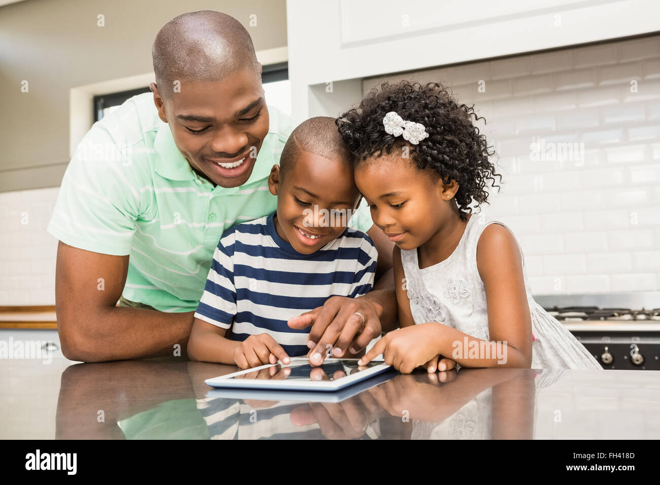 Father using tablet with his children in kitchen Stock Photo - Alamy