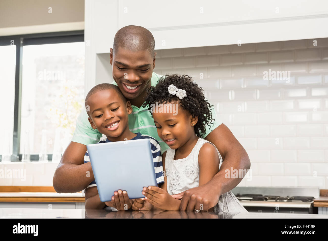 Father using tablet with his children in kitchen Stock Photo - Alamy