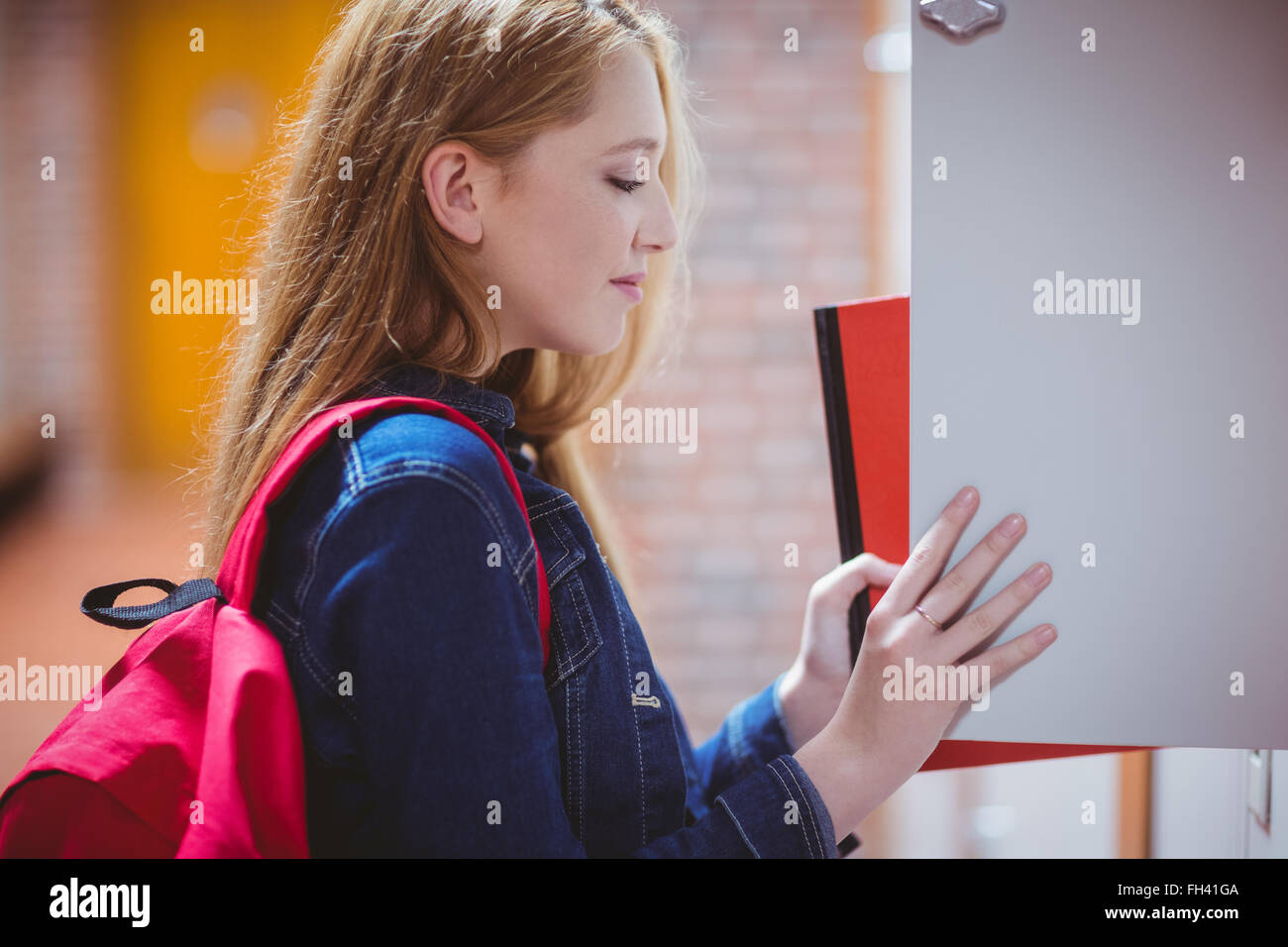 Pretty student with backpack putting notebook in the locker Stock Photo ...