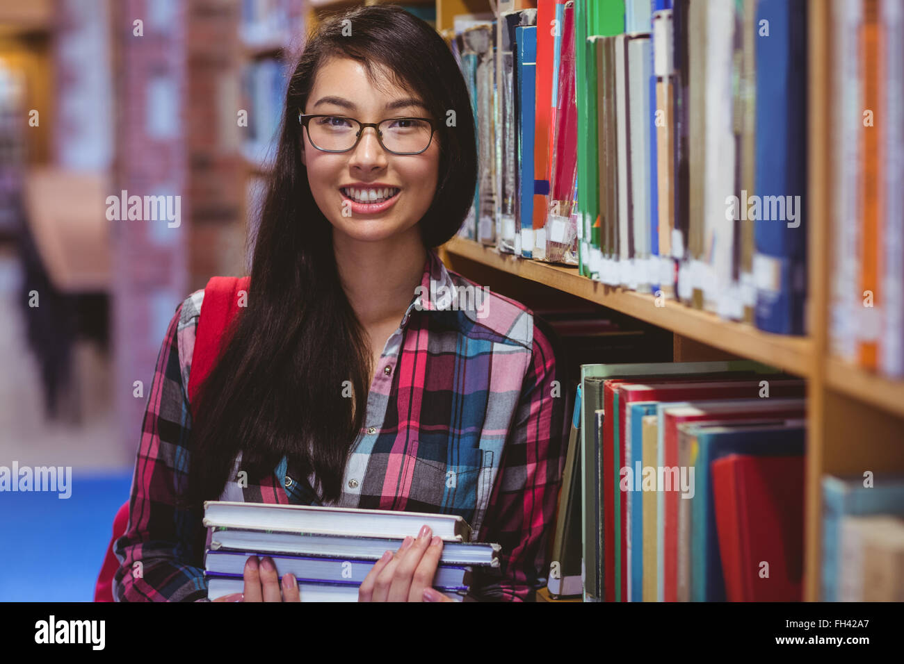 Smiling student holding books in library Stock Photo - Alamy