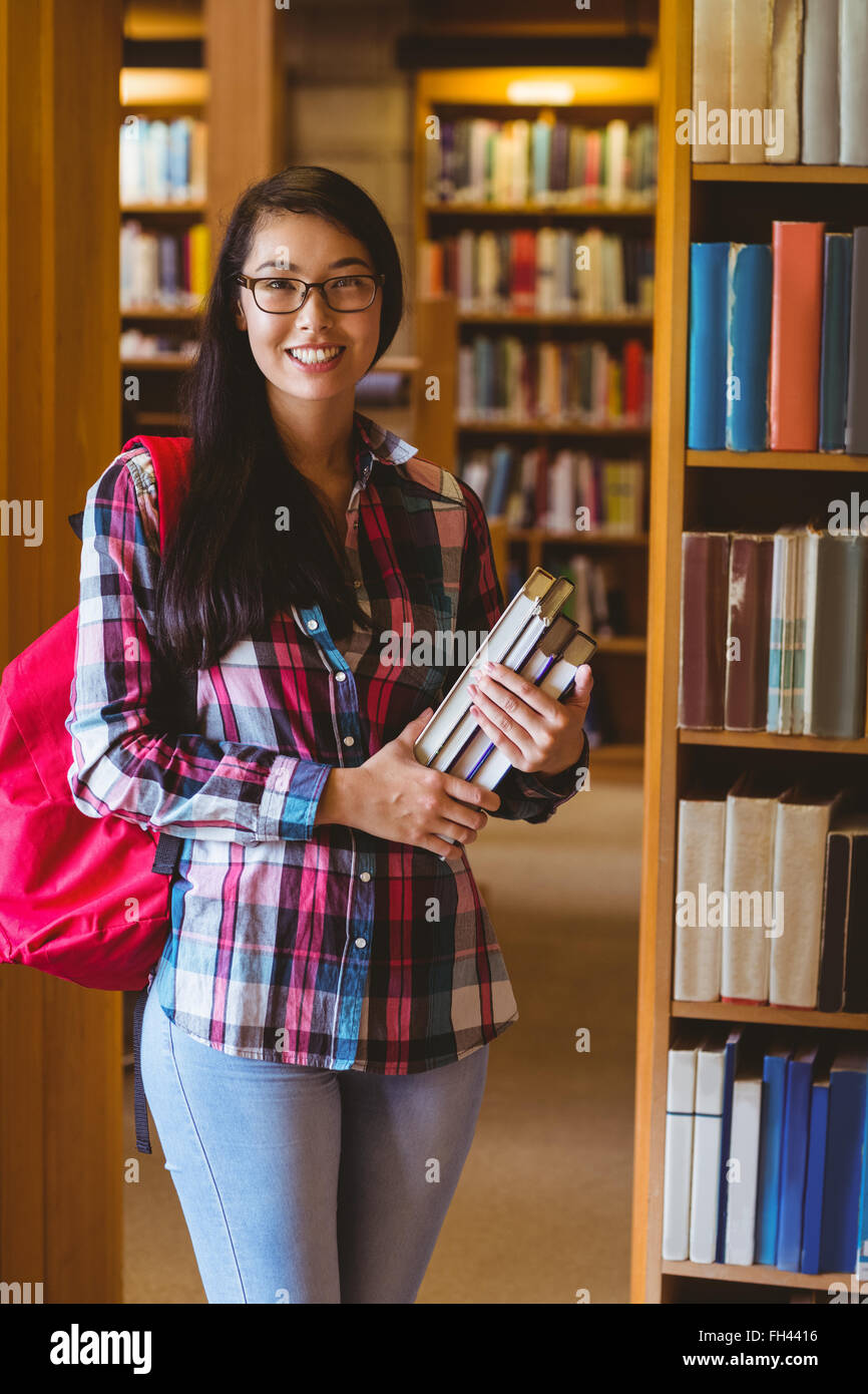 Smiling student holding books in library Stock Photo - Alamy