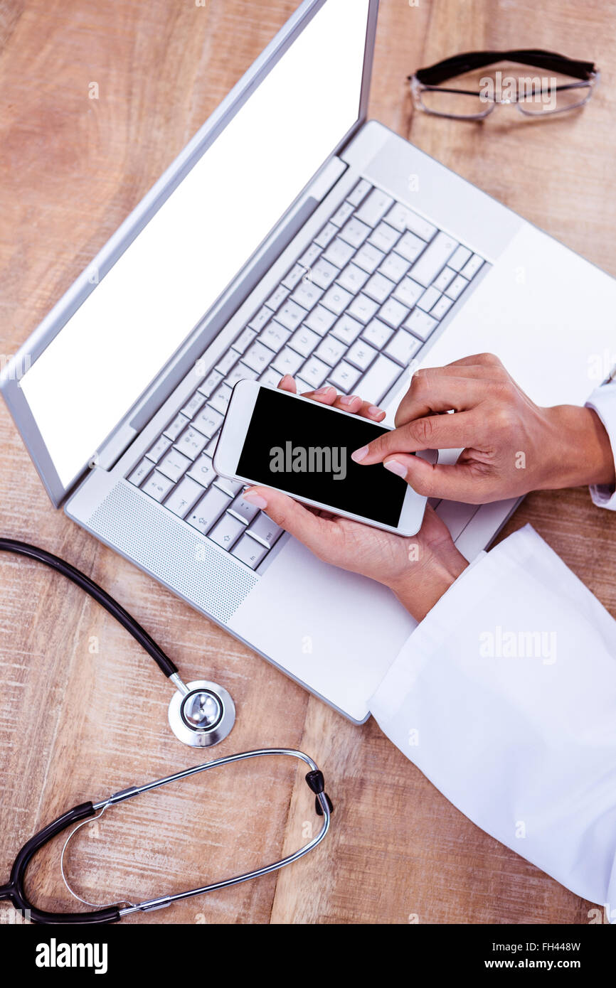 Doctor using smartphone on wooden desk Stock Photo - Alamy