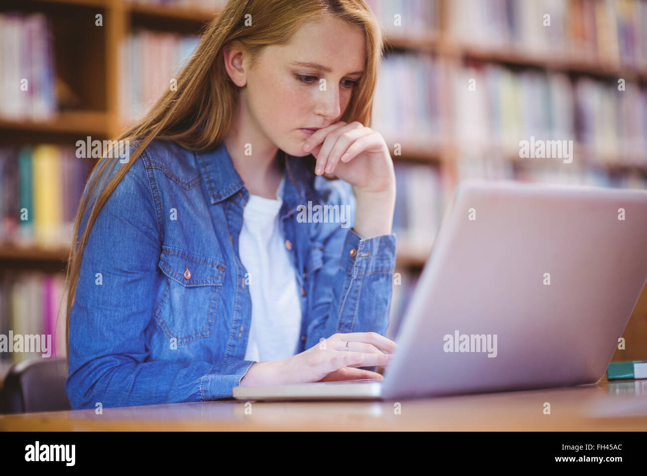 Focused student using laptop in library Stock Photo - Alamy