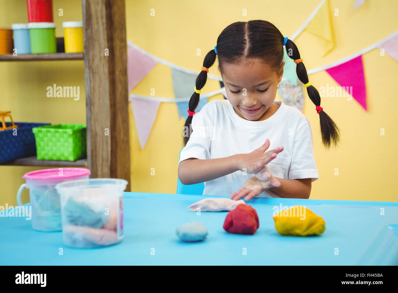Happy girl rolling modelling clay Stock Photo - Alamy