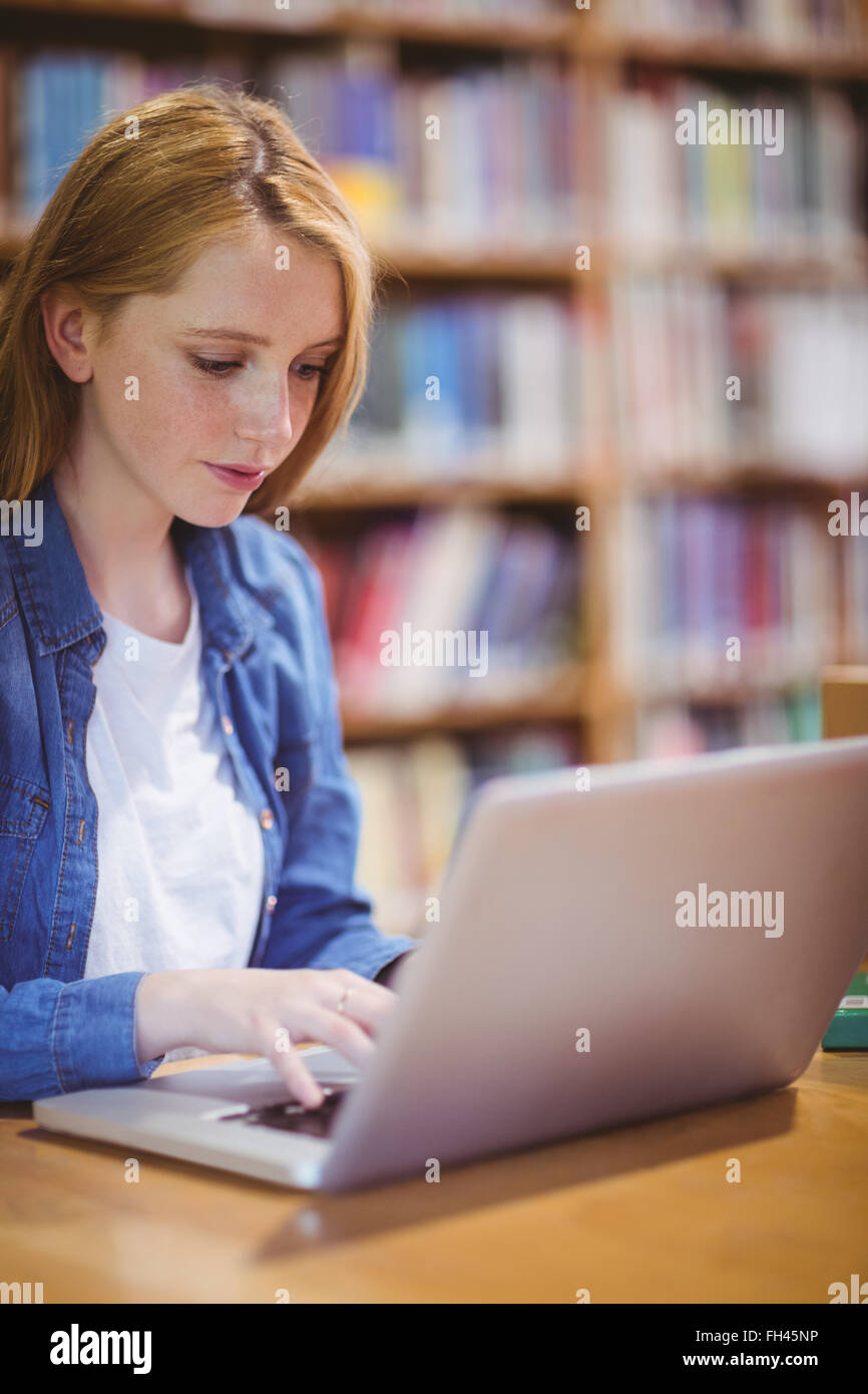 Blond student using laptop in library Stock Photo - Alamy