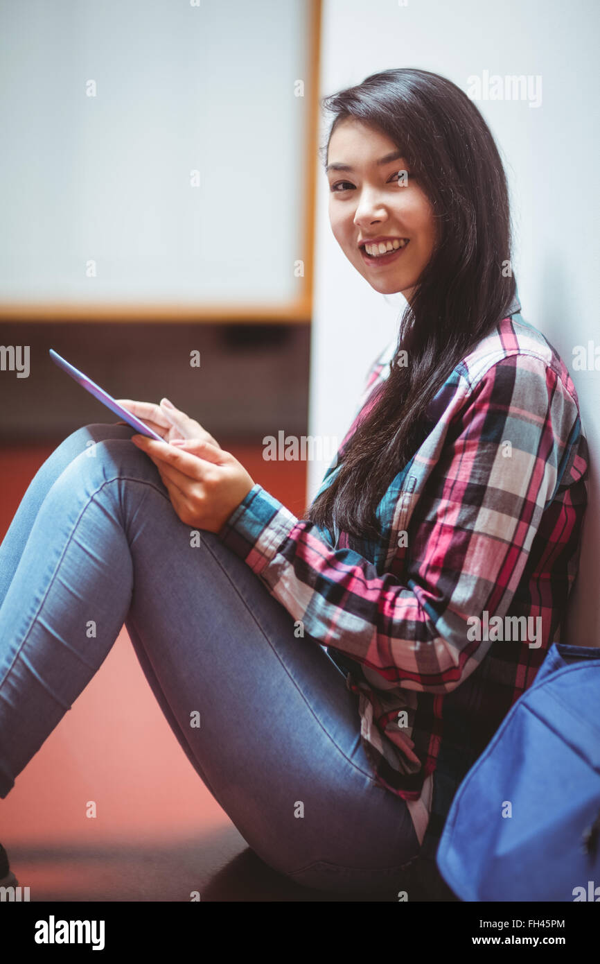 Smiling student sitting on the floor and using tablet Stock Photo - Alamy