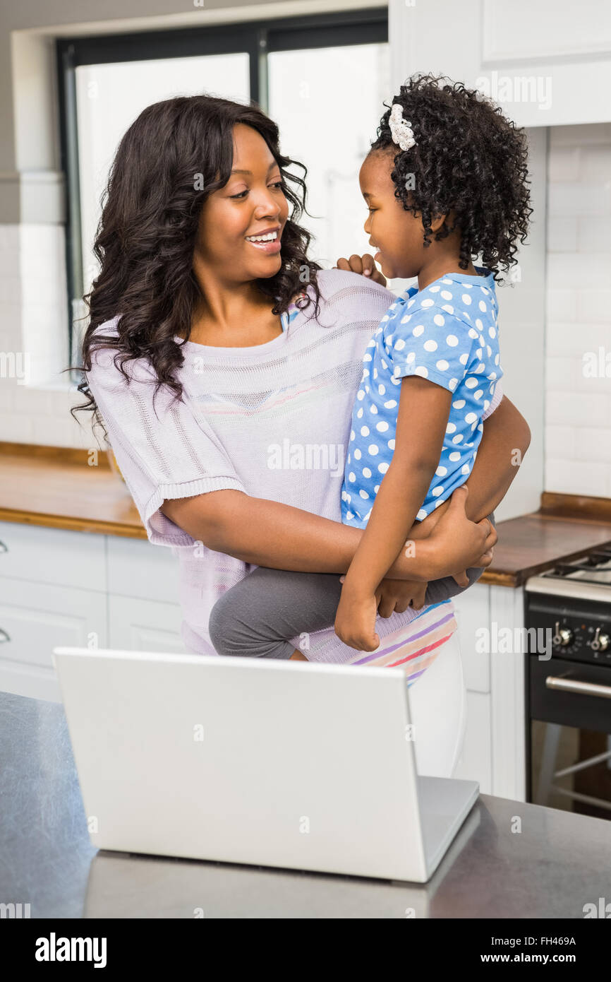 Mother using laptop while carrying kid Stock Photo - Alamy