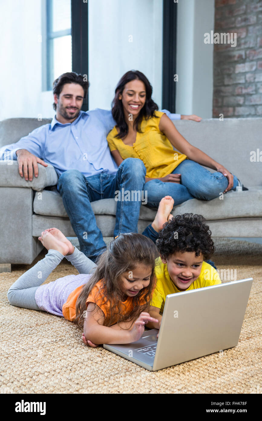Children laying on carpet in living room using laptop Stock Photo - Alamy