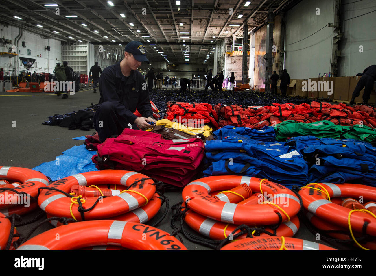 Seaman William Thorpe inspects a flight deck life-preserver in the hangar bay of USS Dwight D ...