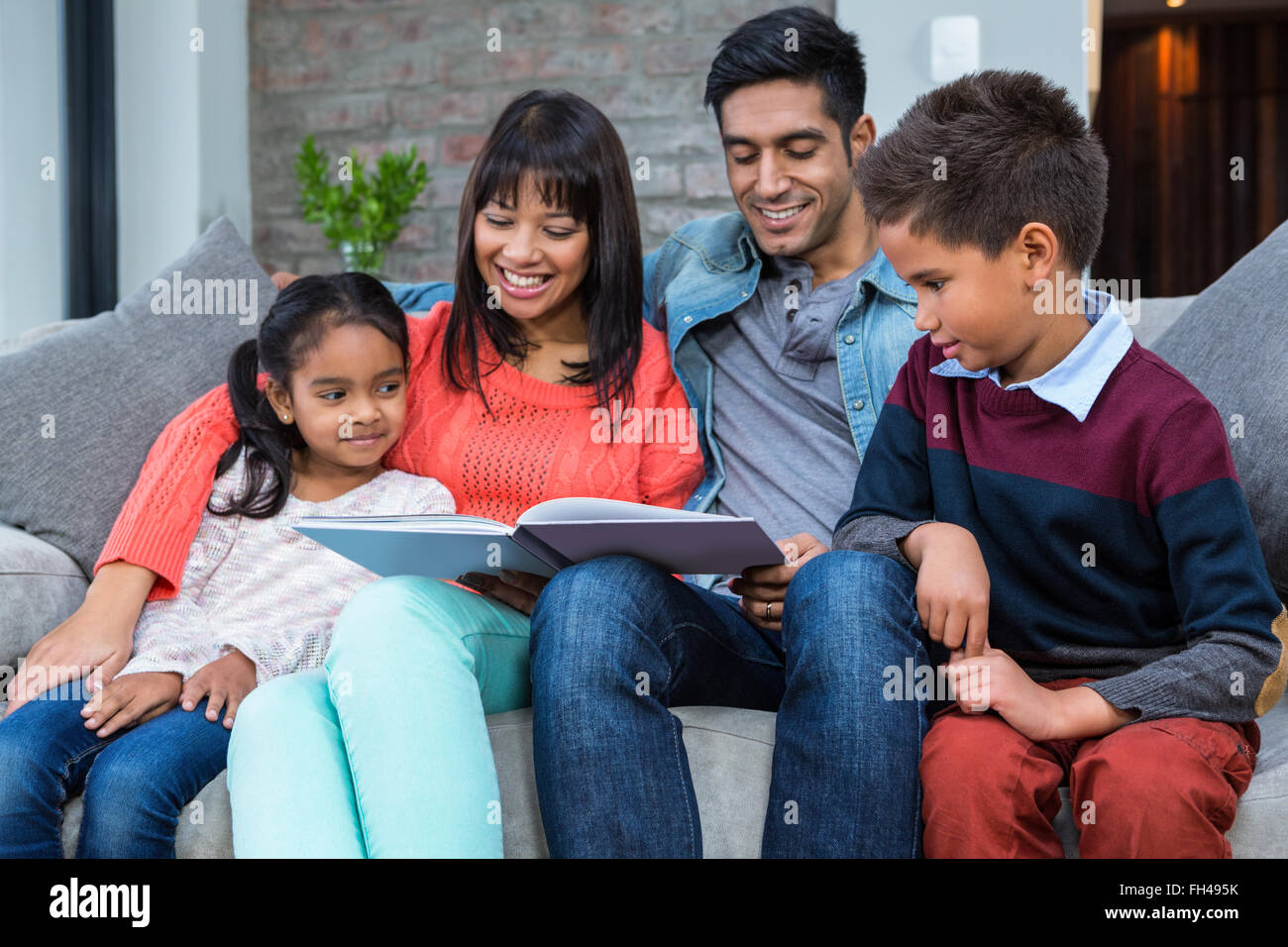 Happy young family reading a book together Stock Photo - Alamy