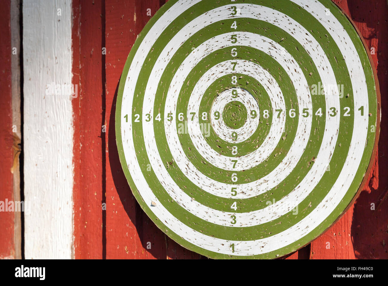 Old darts target hanging on red wooden wall Stock Photo - Alamy