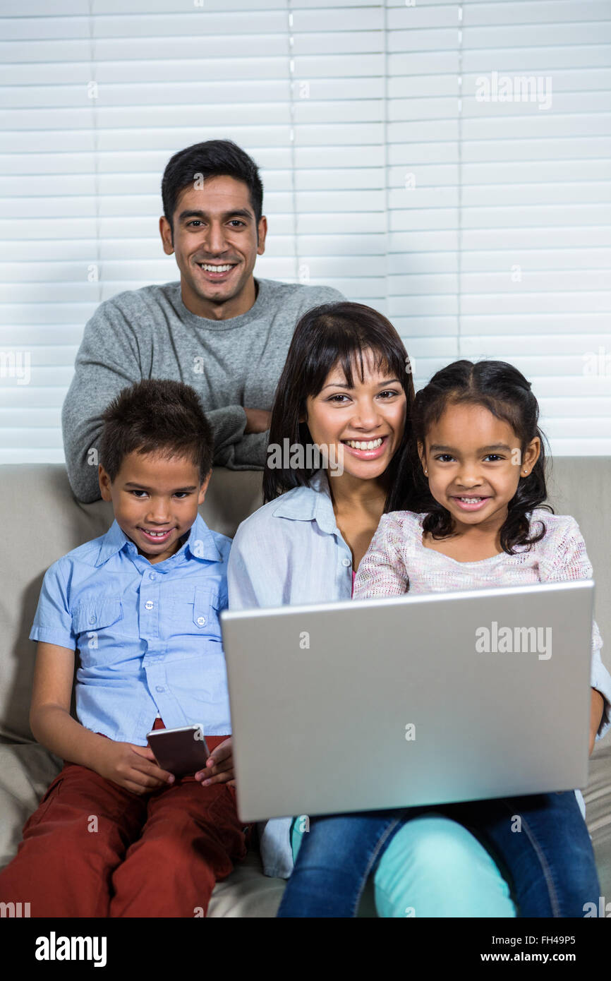 Smiling family using technology on the sofa Stock Photo - Alamy