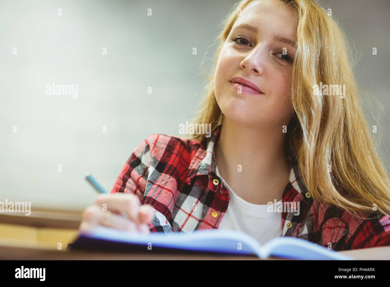 Smiling student writing on notebok Stock Photo - Alamy