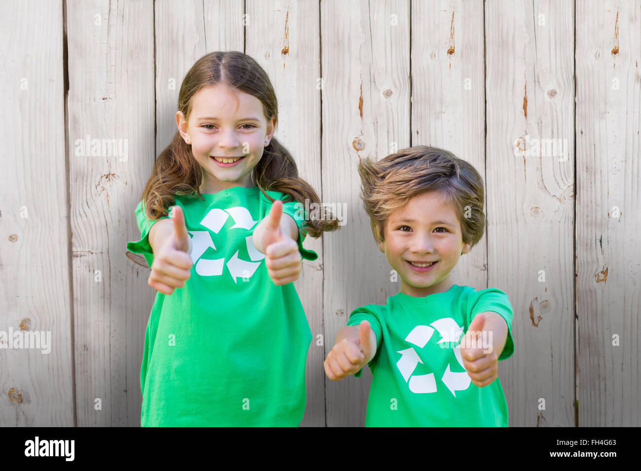 Composite image of happy siblings in green with thumbs up Stock Photo ...