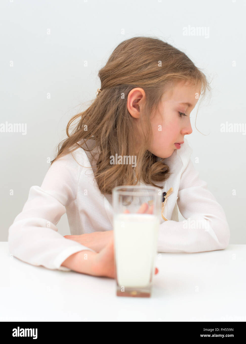 Sad little girl with glass of milk Stock Photo - Alamy