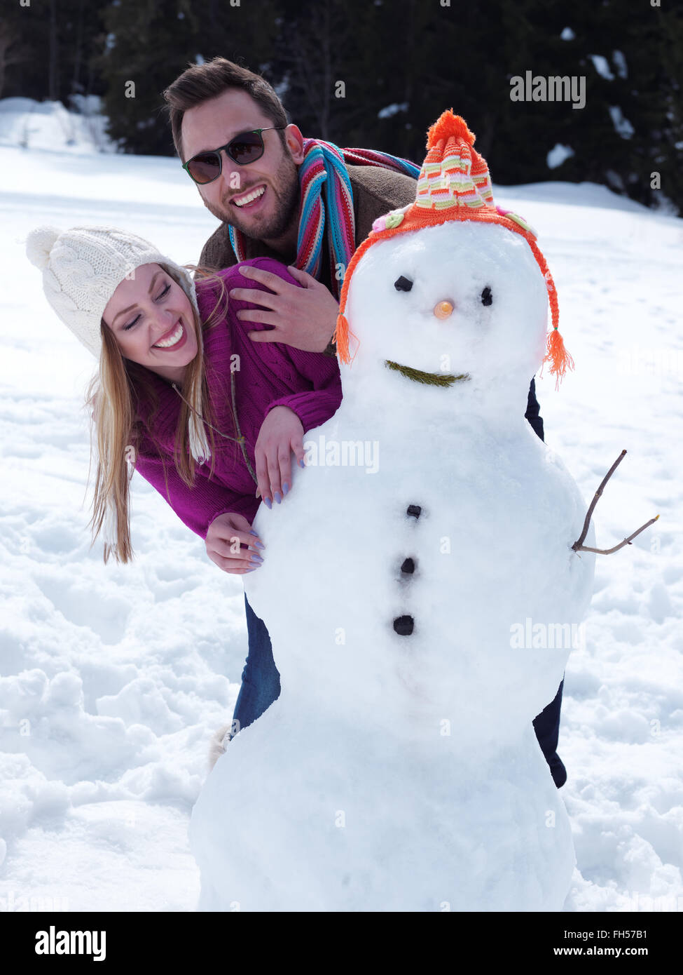 portrait of happy young couple with snowman Stock Photo - Alamy
